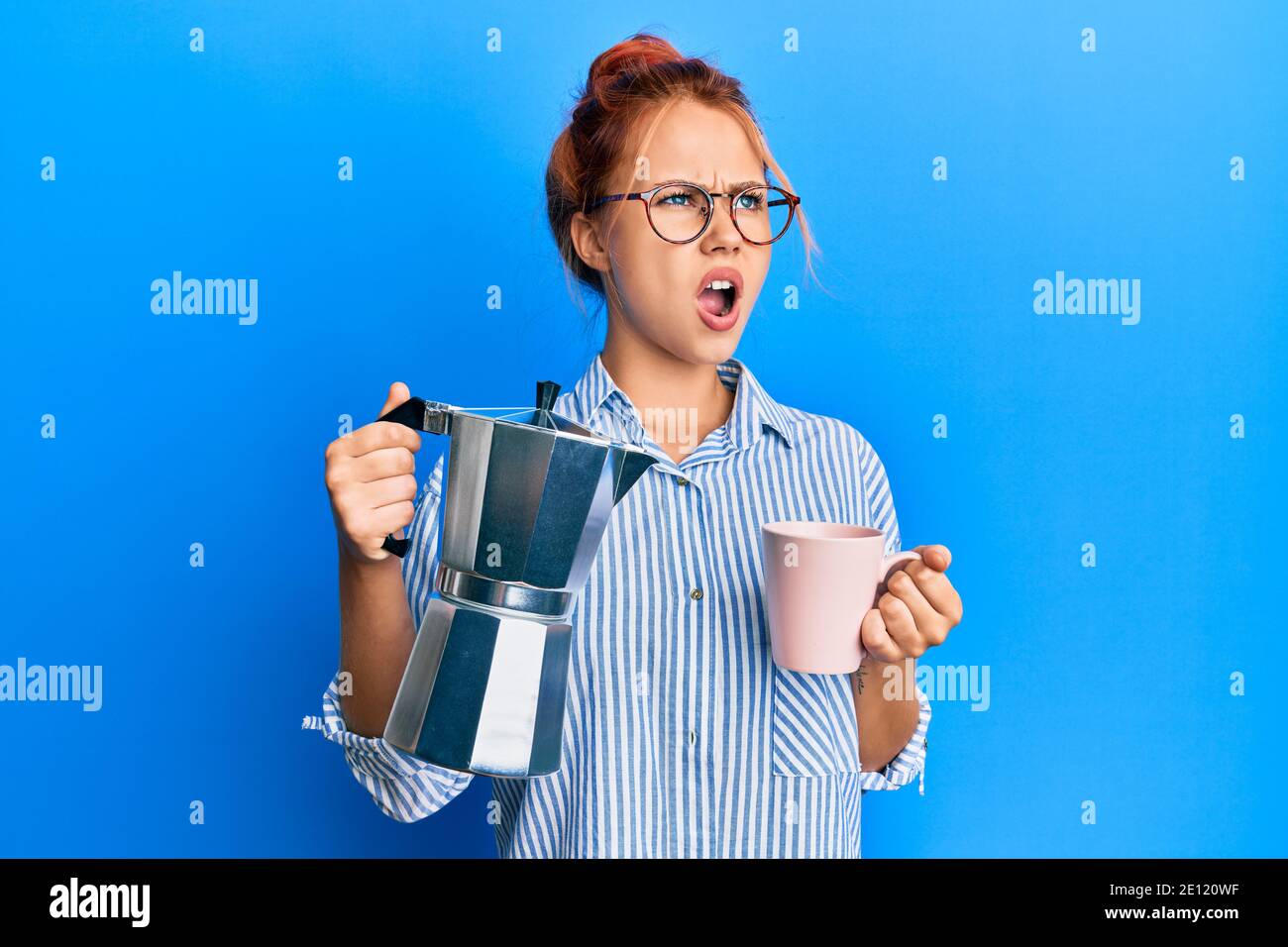 Young redhead woman drinking italian coffee angry and mad screaming ...