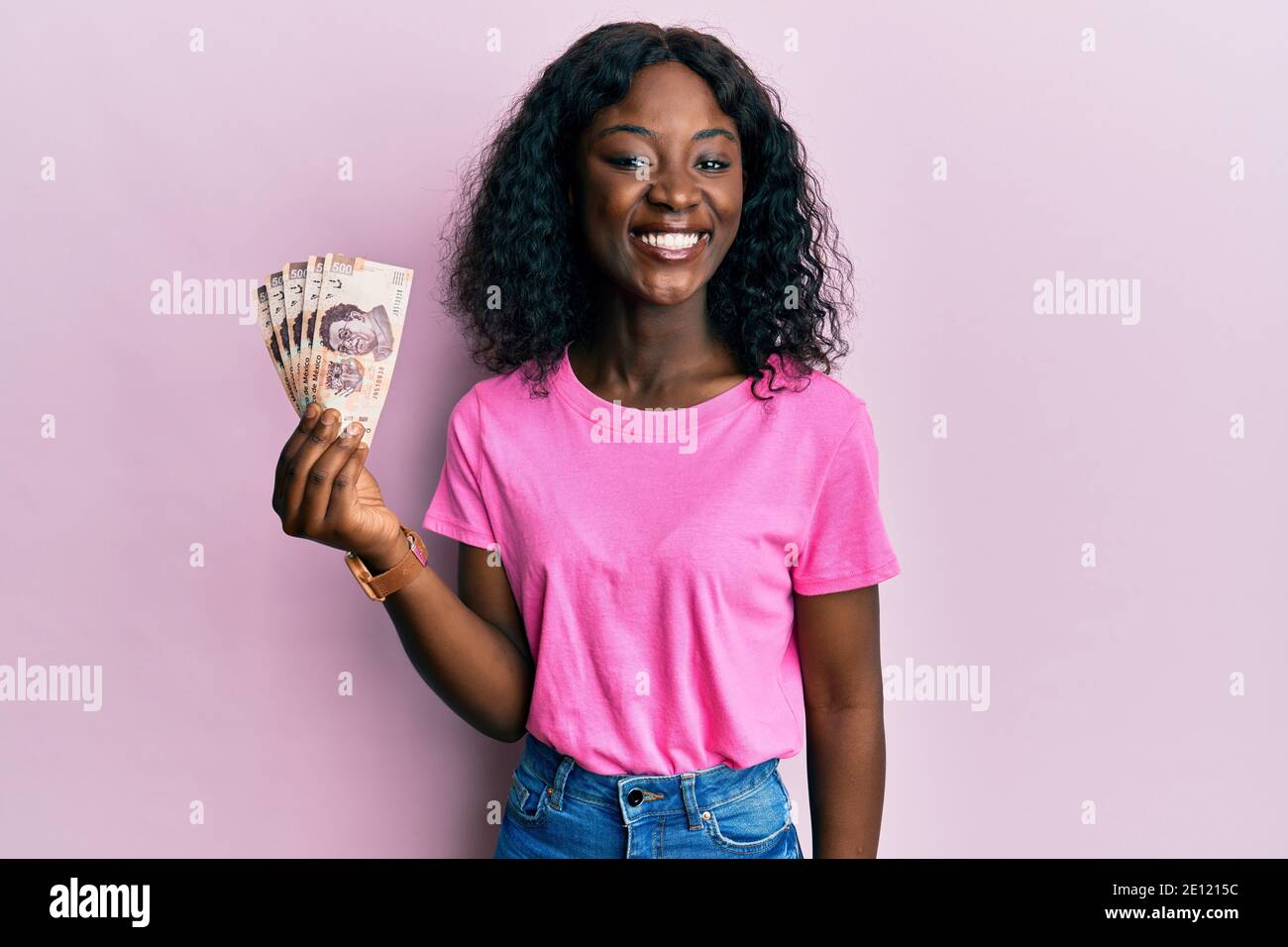 Beautiful african young woman holding 500 mexican pesos banknotes ...