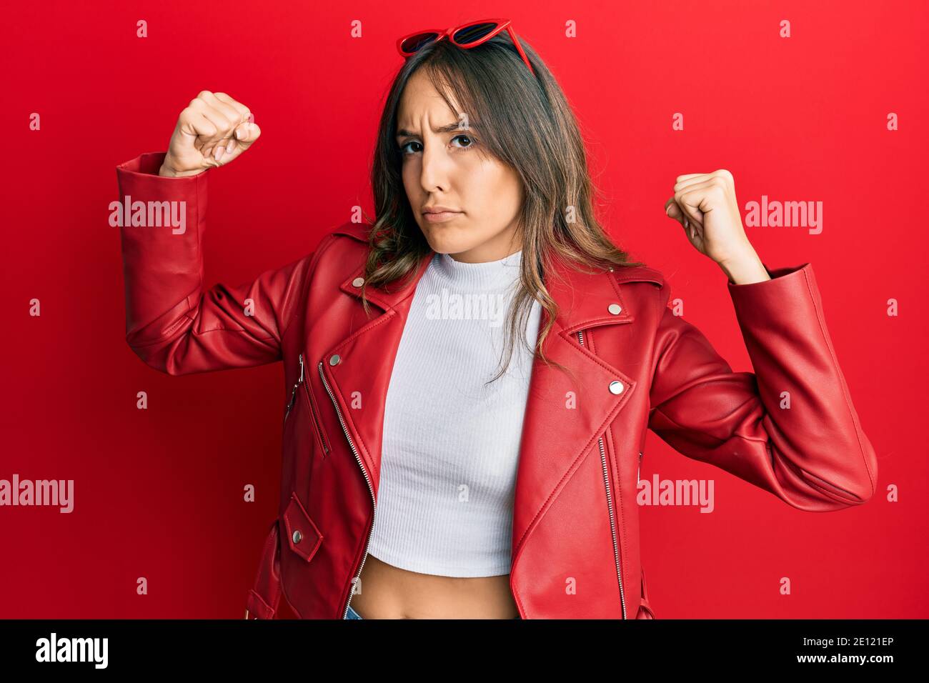 Young brunette woman wearing red leather jacket showing arms muscles ...