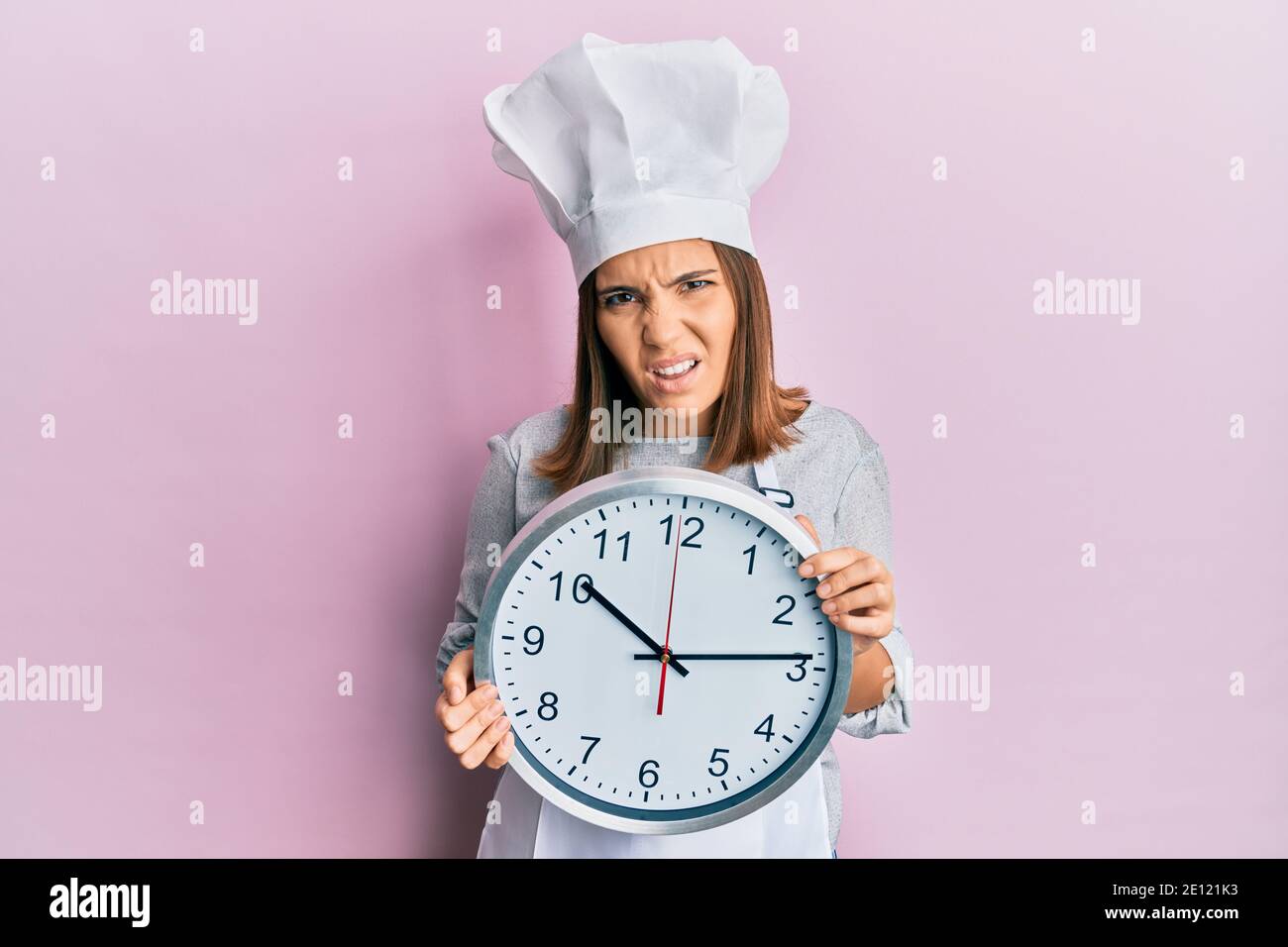 Young beautiful woman wearing professional cook uniform and hat holding ...
