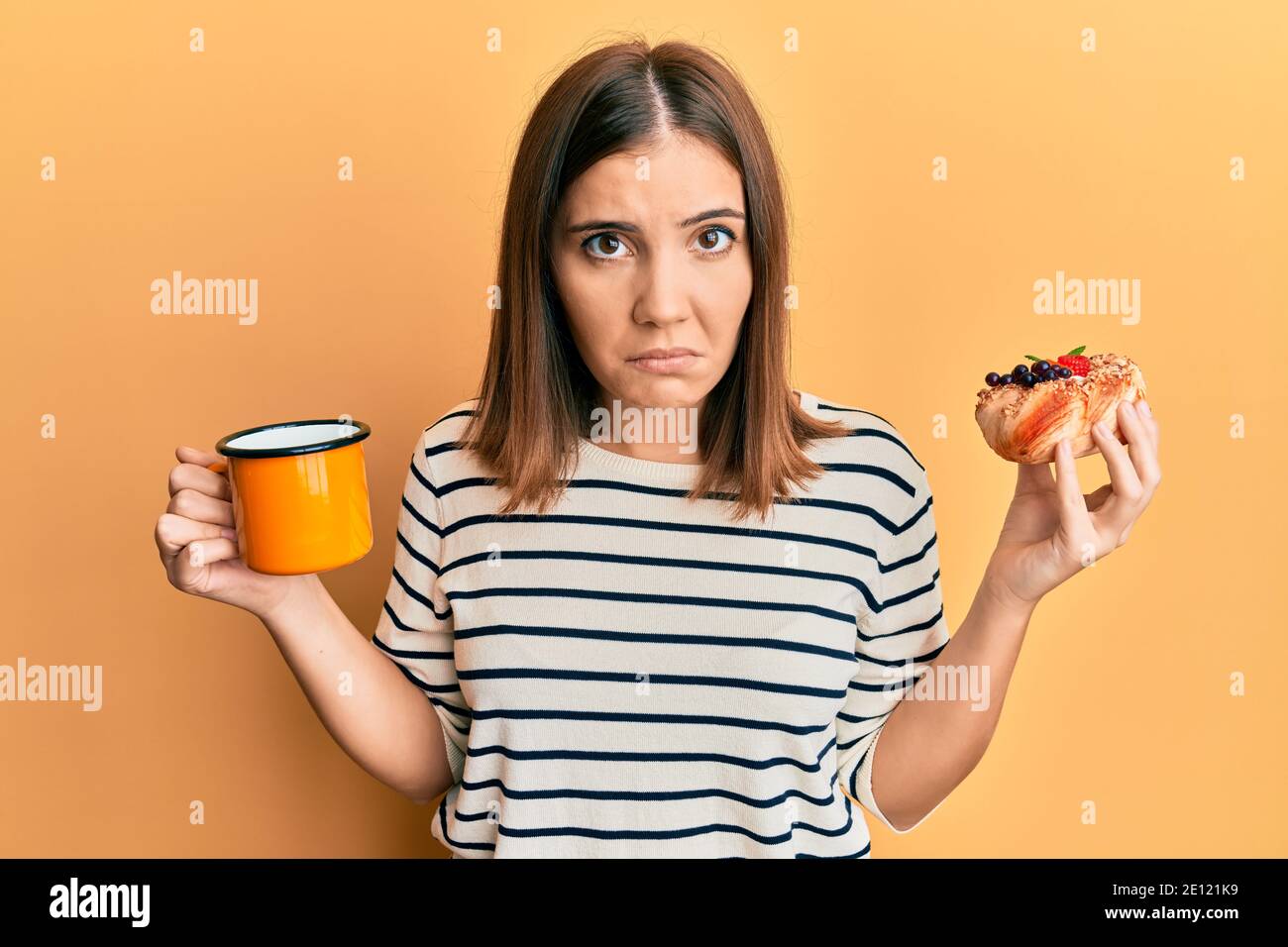 Young beautiful woman drinking coffee and eating pastry depressed and ...