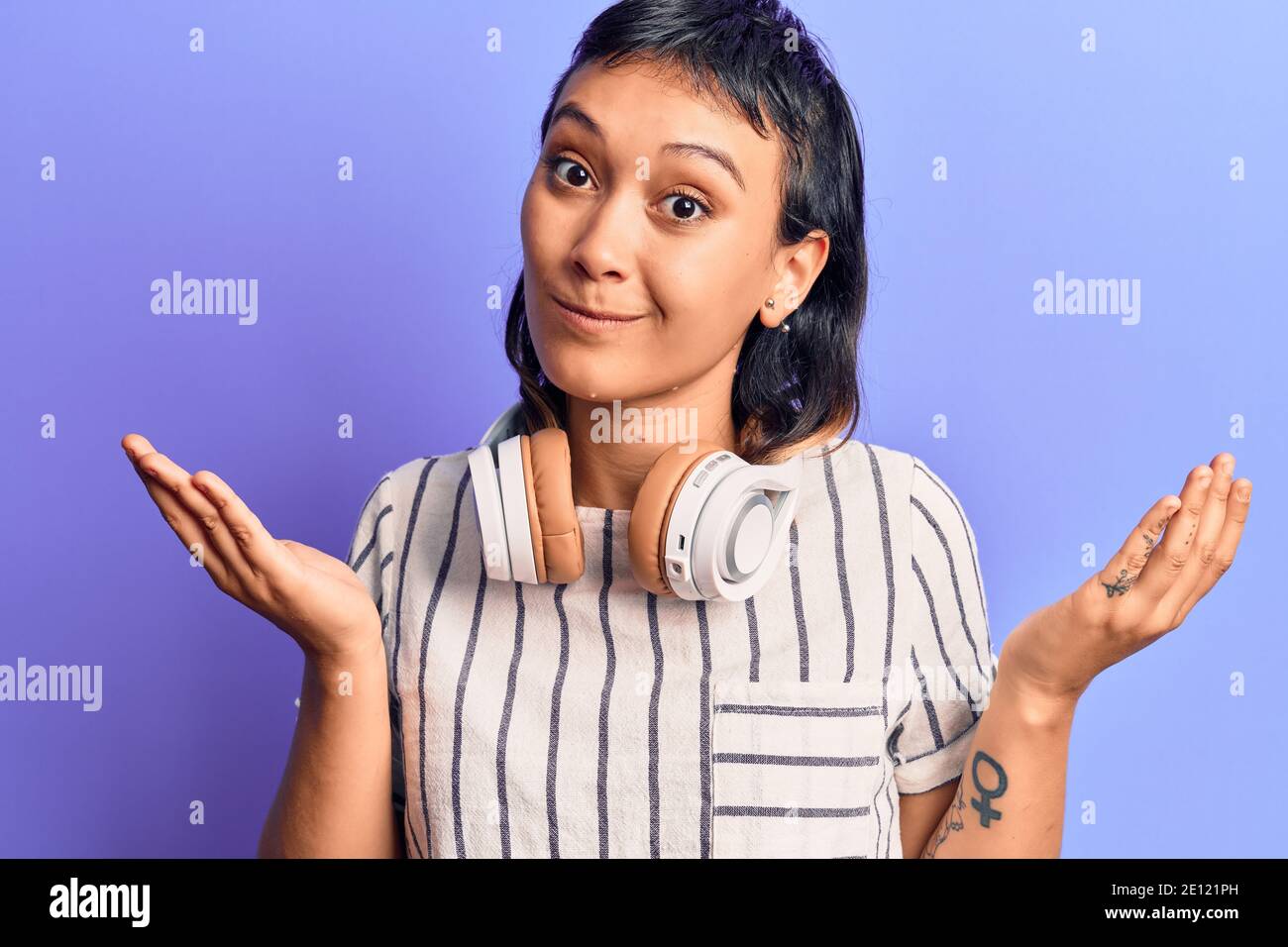 Young woman listening to music using headphones clueless and confused ...