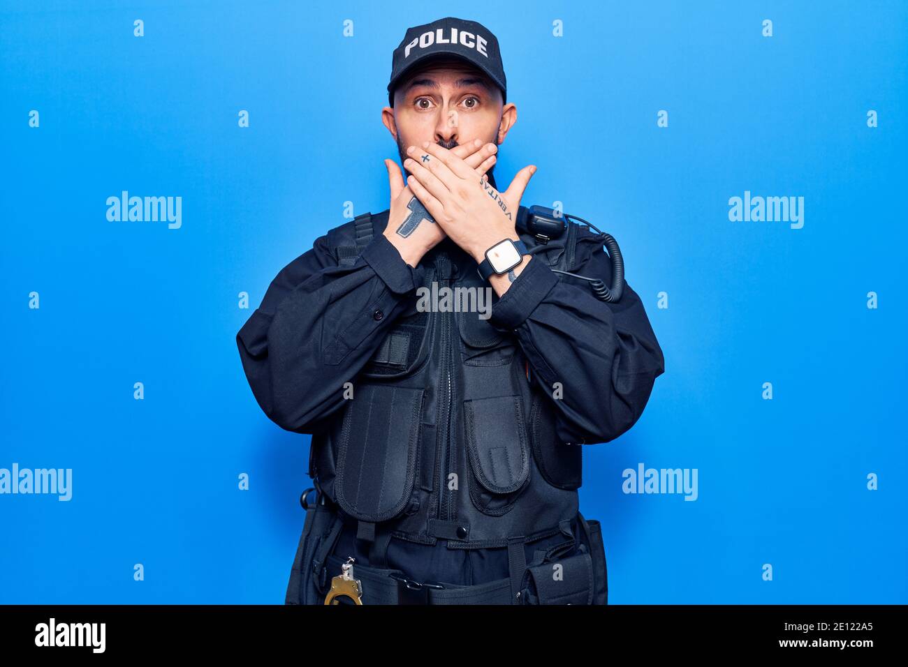 Young handsome man wearing police uniform shocked covering mouth with ...