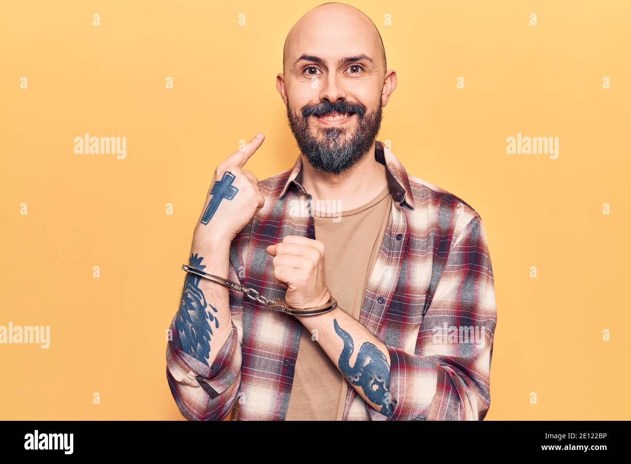 Young handsome man wearing prisoner handcuffs pointing finger to one ...