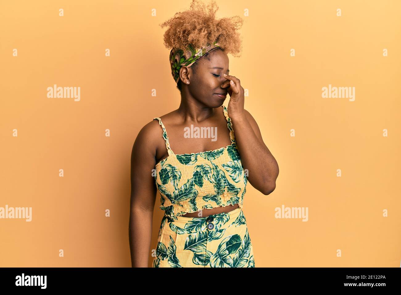 Young african woman with afro hair wearing summer dress smelling ...
