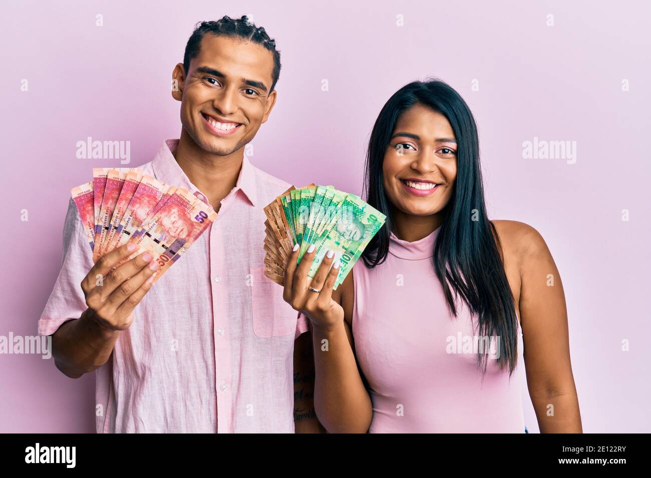 Young latin couple holding south african rand banknotes looking ...