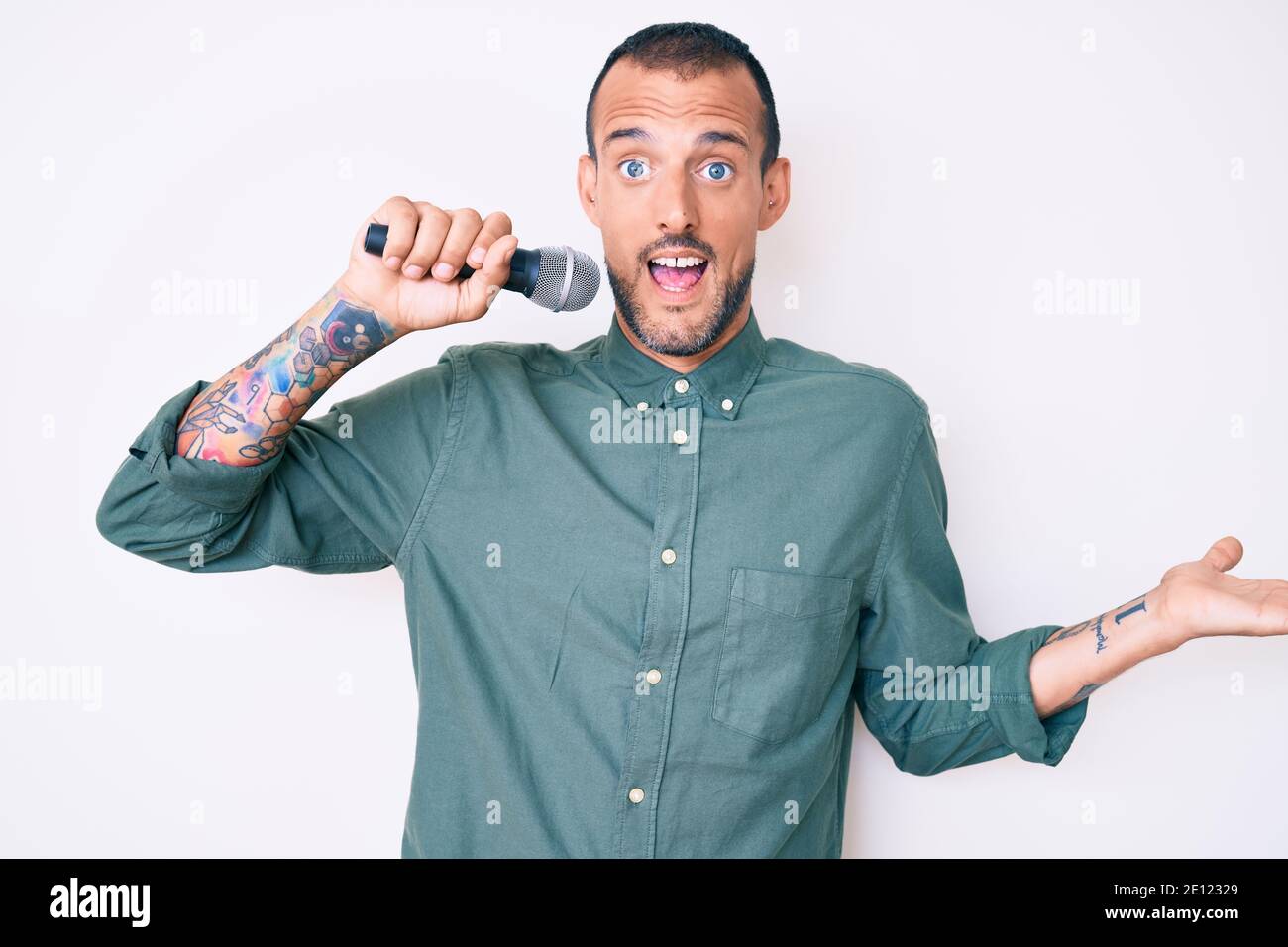 Young handsome man with tattoo singing song using microphone ...