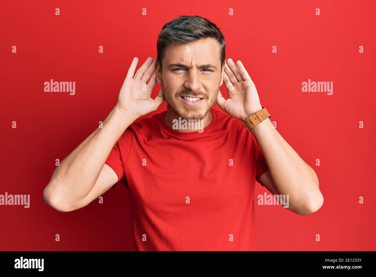 Handsome caucasian man wearing casual red tshirt trying to hear both ...