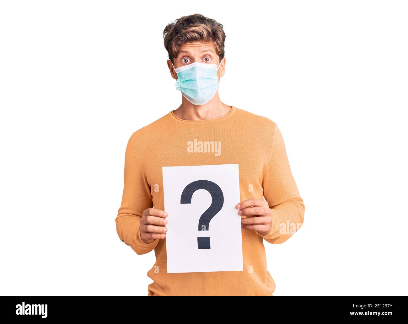 Young handsome man wearing medical mask holding question mark scared ...