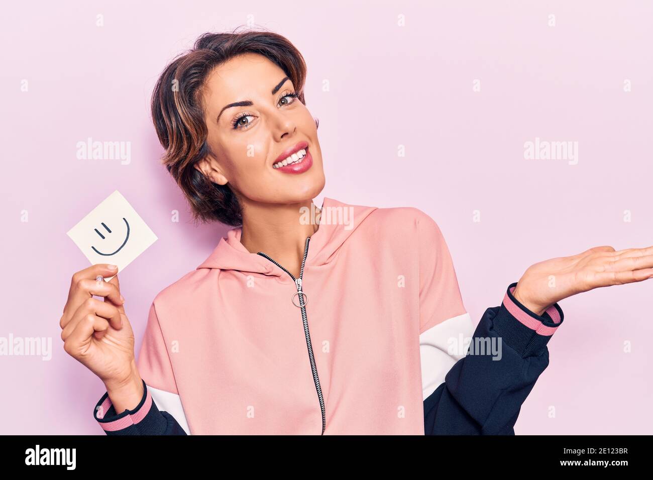 Young beautiful woman holding smile emoji reminder celebrating ...