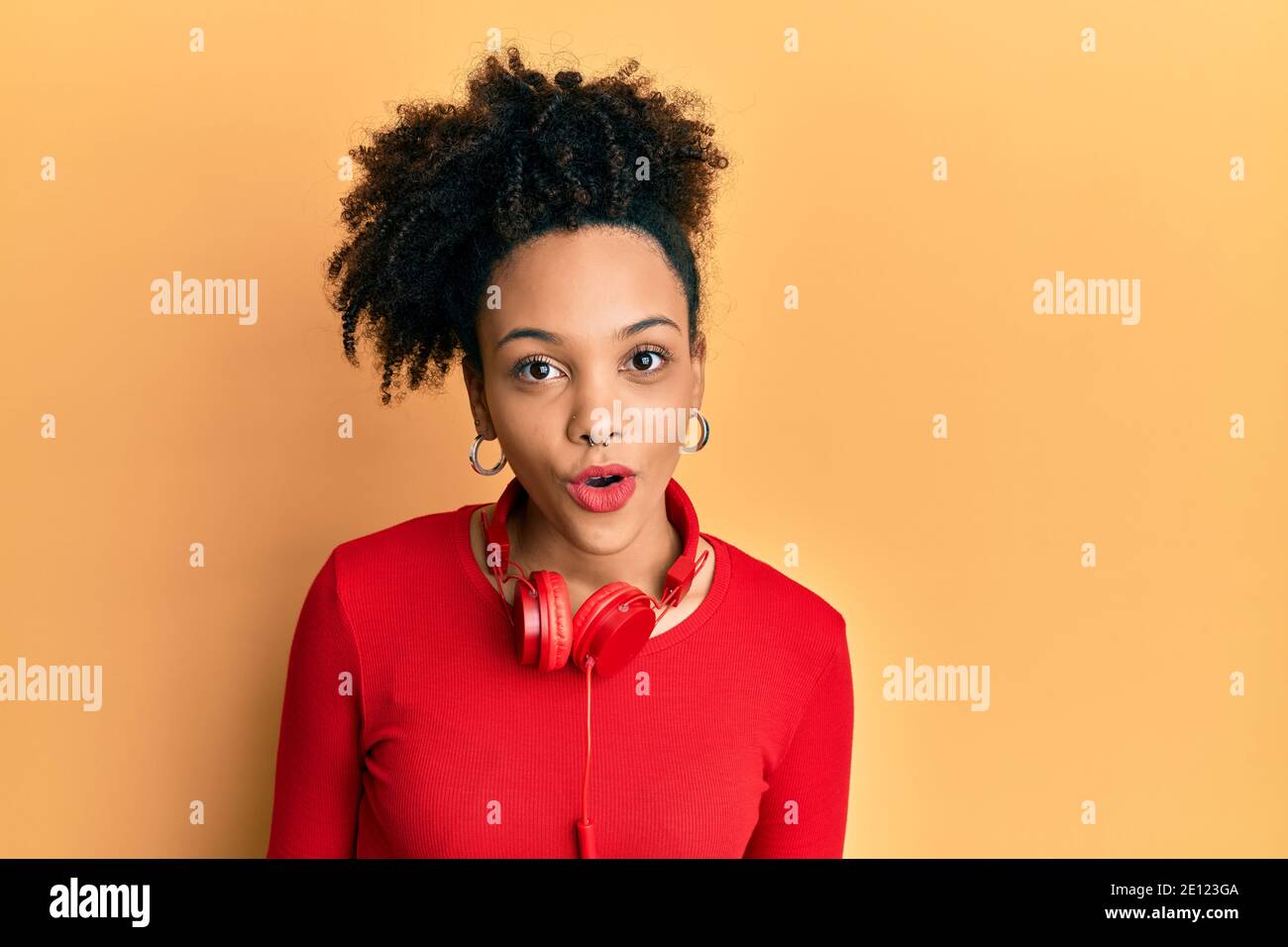 Young african american girl listening to music using headphones scared ...