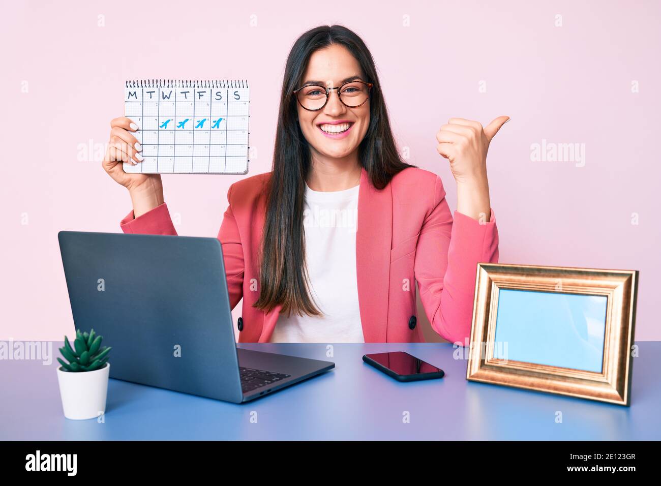 Young caucasian woman sitting at the desk holding travel calendar ...
