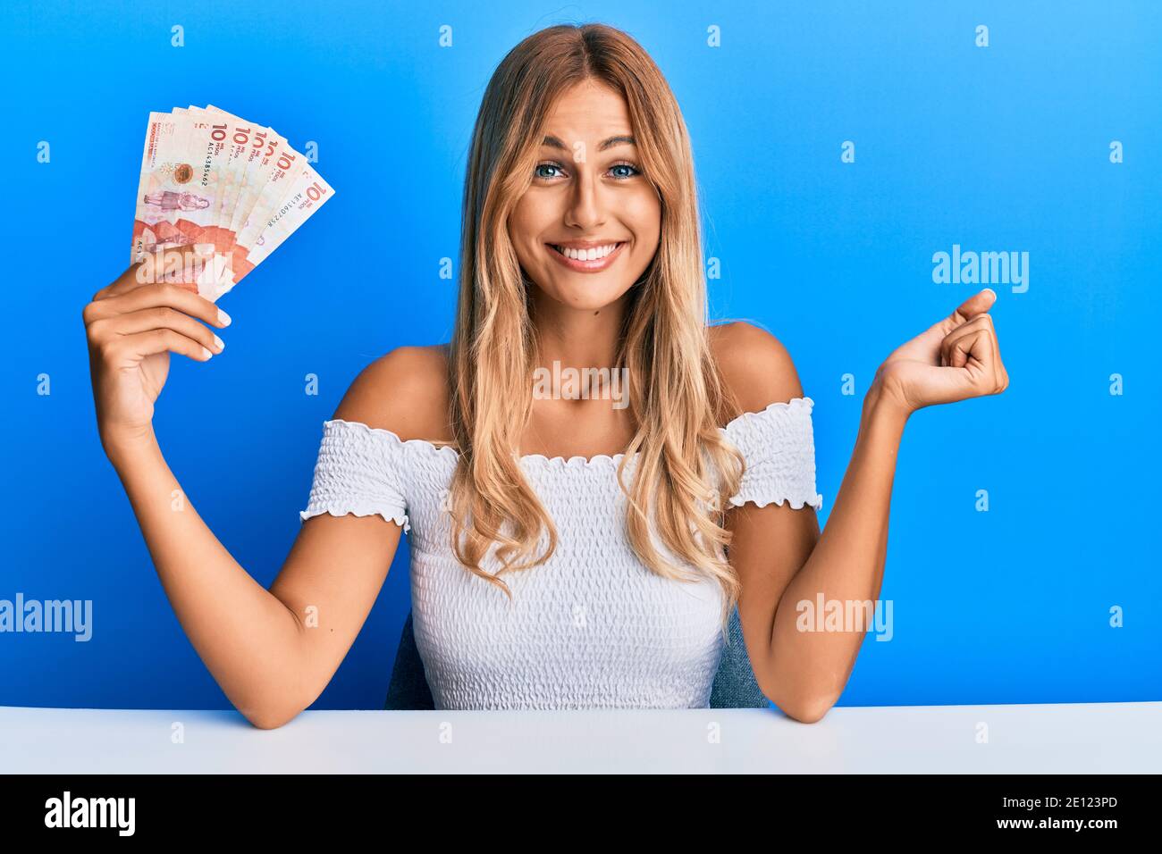 Beautiful blonde young woman holding 10 colombian pesos banknotes ...
