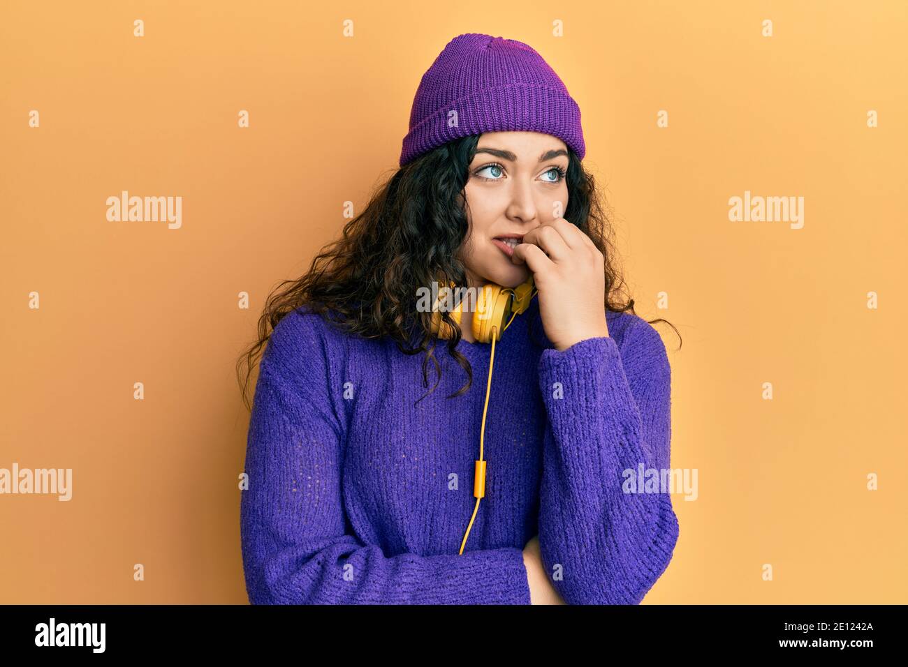 Young brunette woman with curly hair listening to music using ...