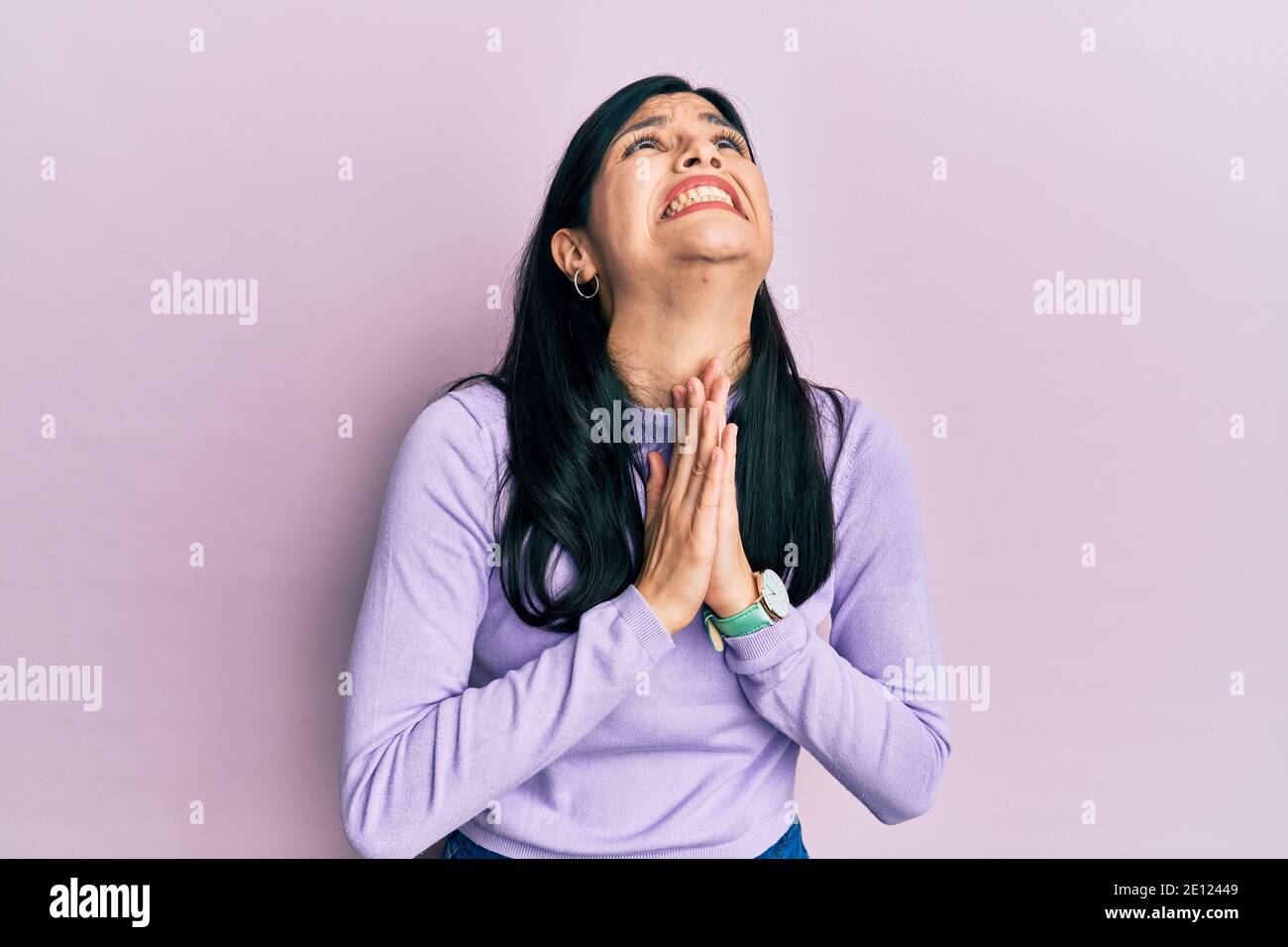 Young hispanic woman wearing casual clothes begging and praying with ...