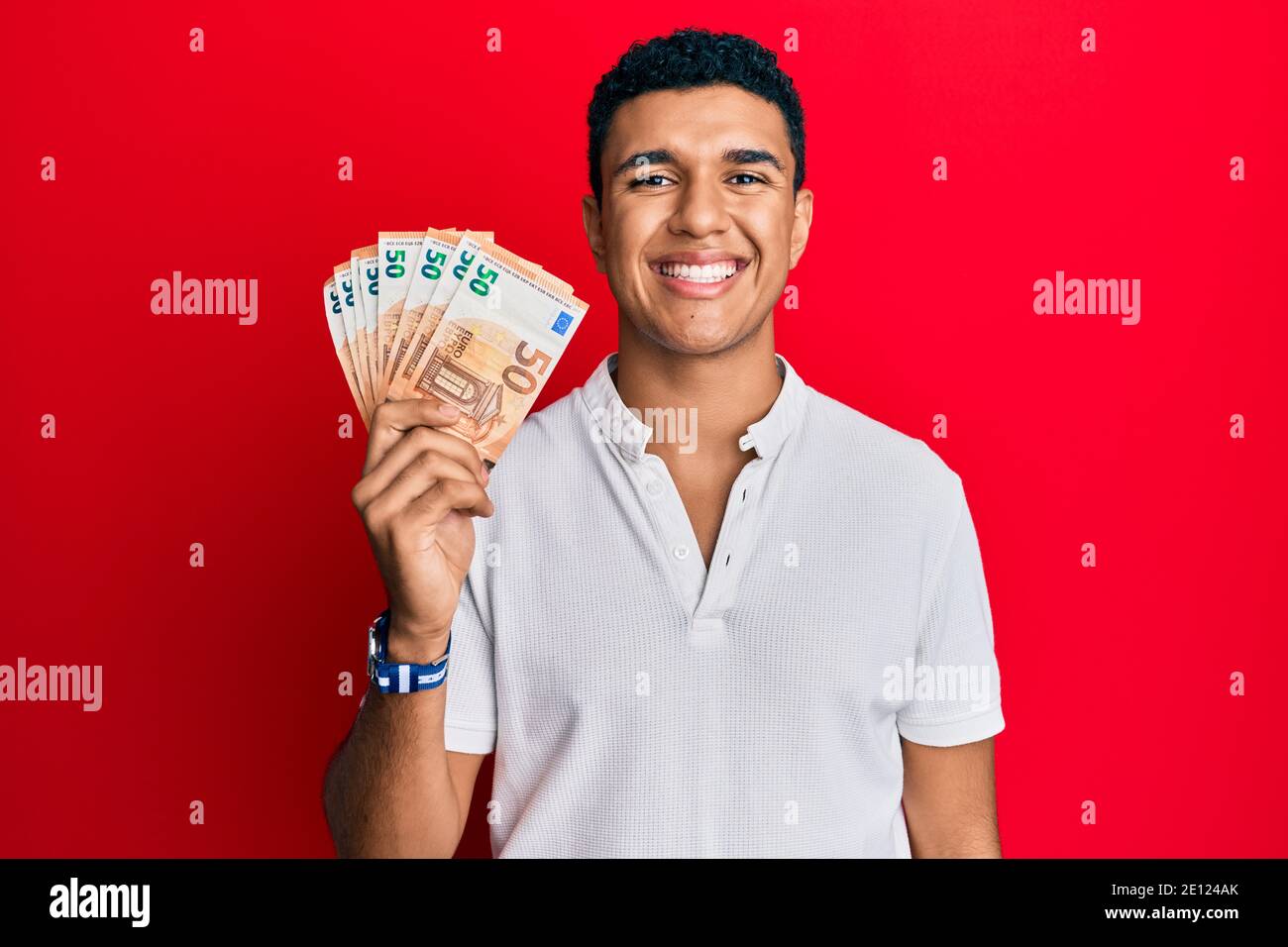 Young arab man holding 50 euro banknotes looking positive and happy ...