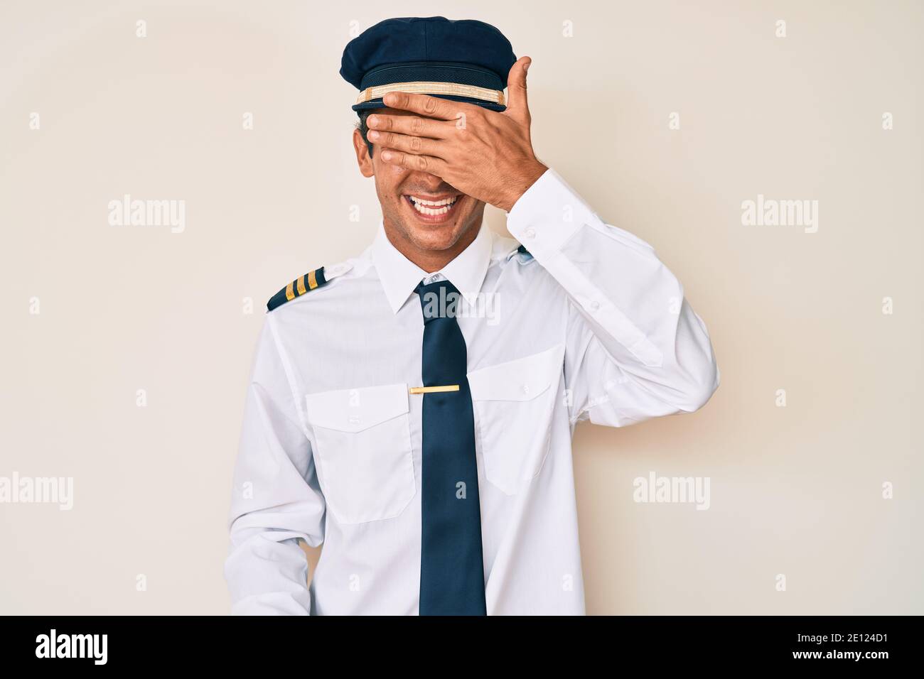 Young hispanic man wearing airplane pilot uniform smiling and laughing ...