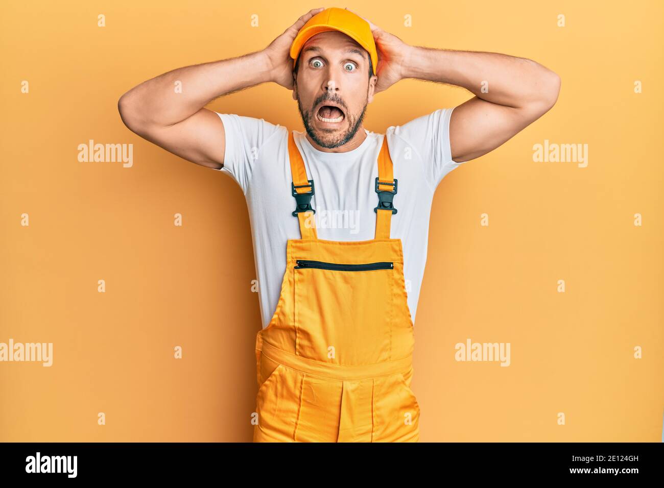 Young handsome man wearing handyman uniform over yellow background ...