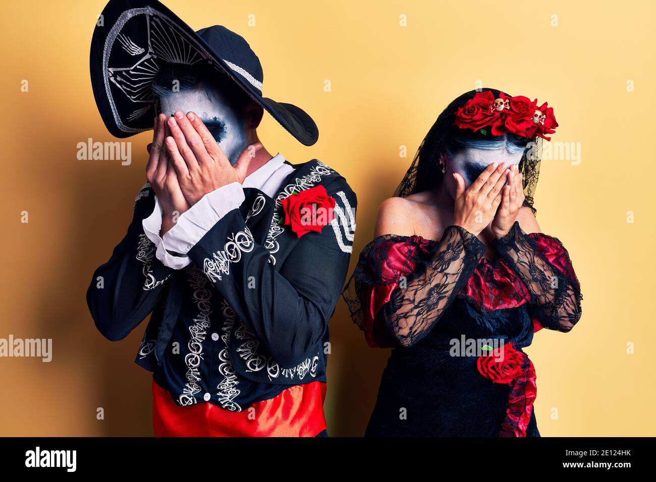 Young couple wearing mexican day of the dead costume over yellow with ...