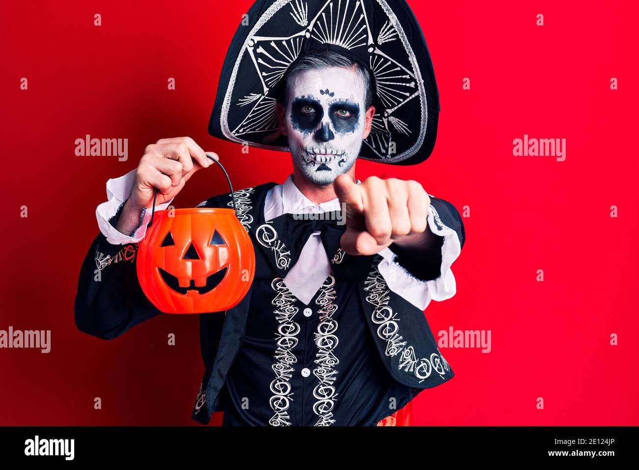 Young man wearing mexican day of the dead costume holding pumpkin ...
