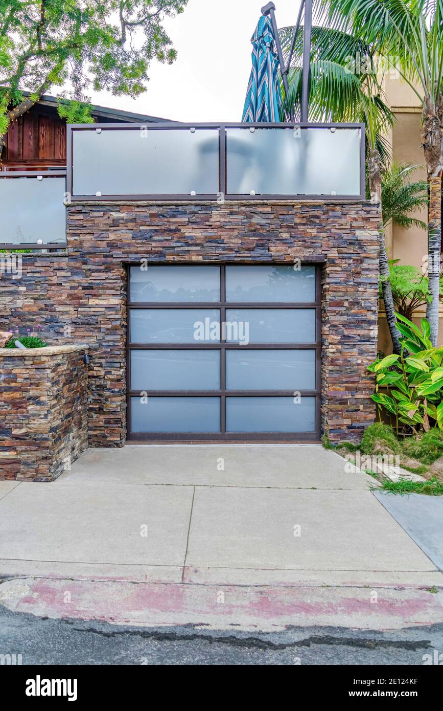House garage with glass paned door under balcony with glass railing in ...