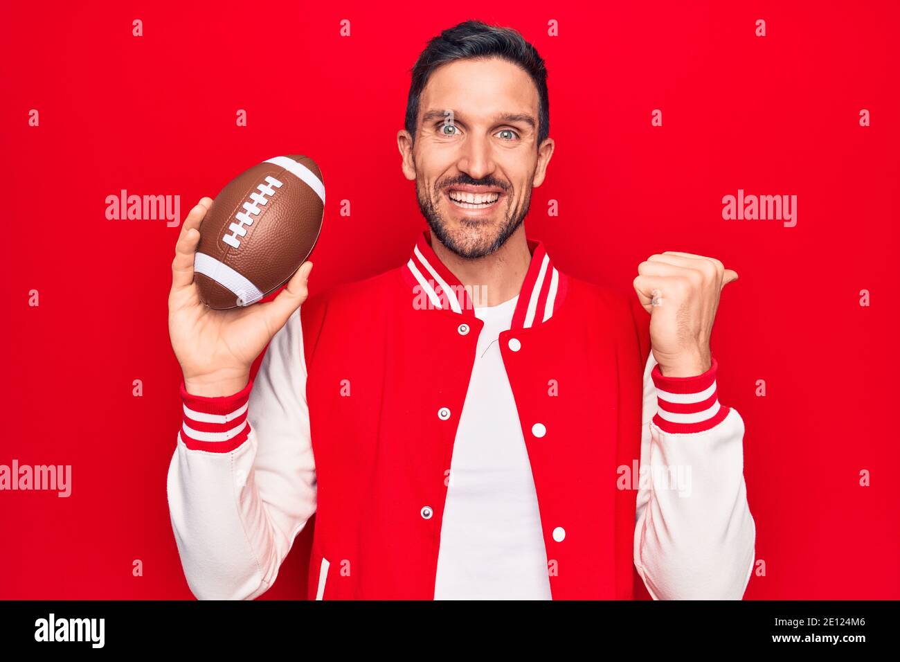 Young handsome player man playing rugby using football ball over ...
