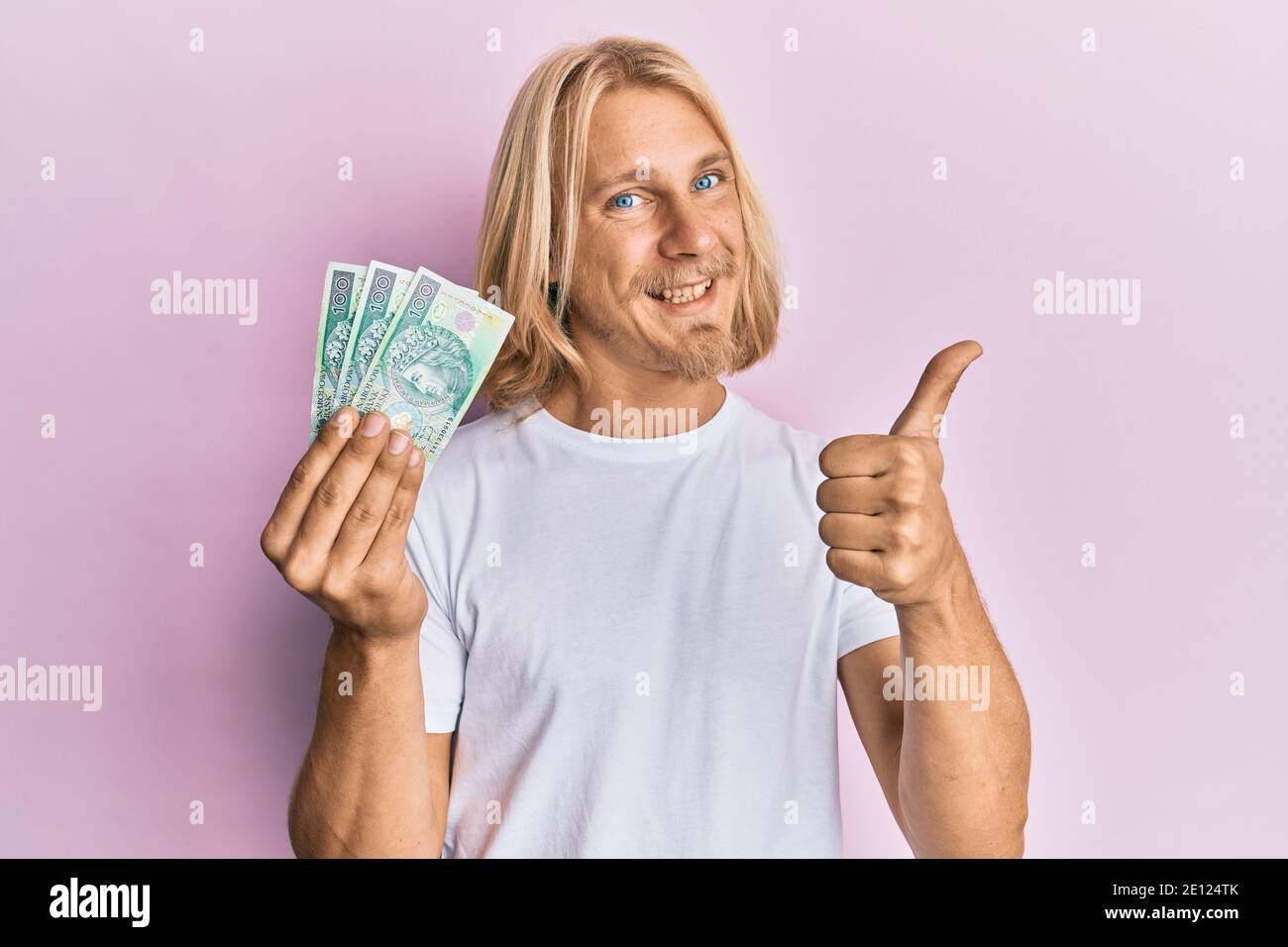 Caucasian young man with long hair holding 100 polish zloty banknotes ...