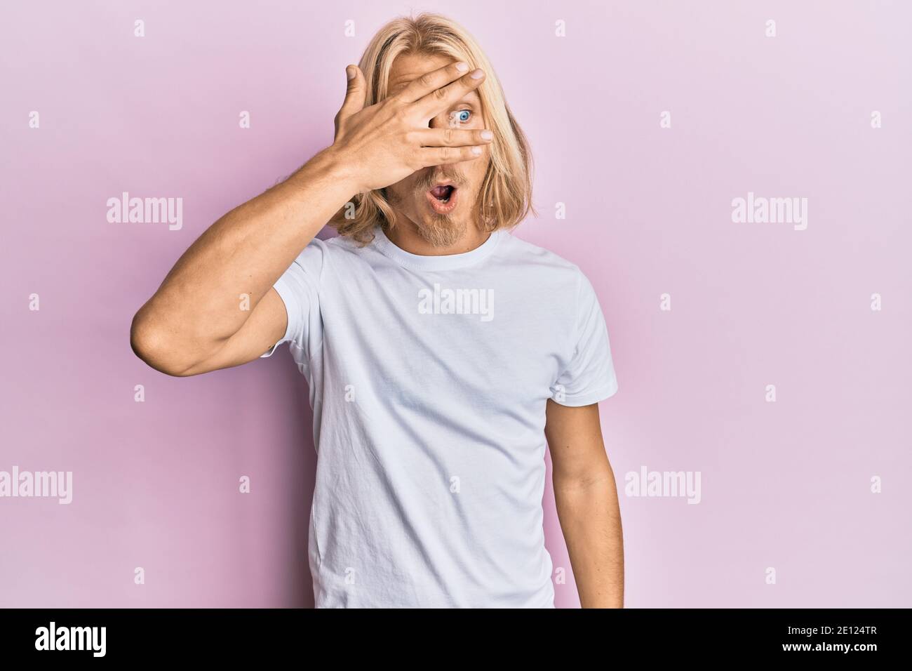 Caucasian young man with long hair wearing casual white t shirt peeking ...