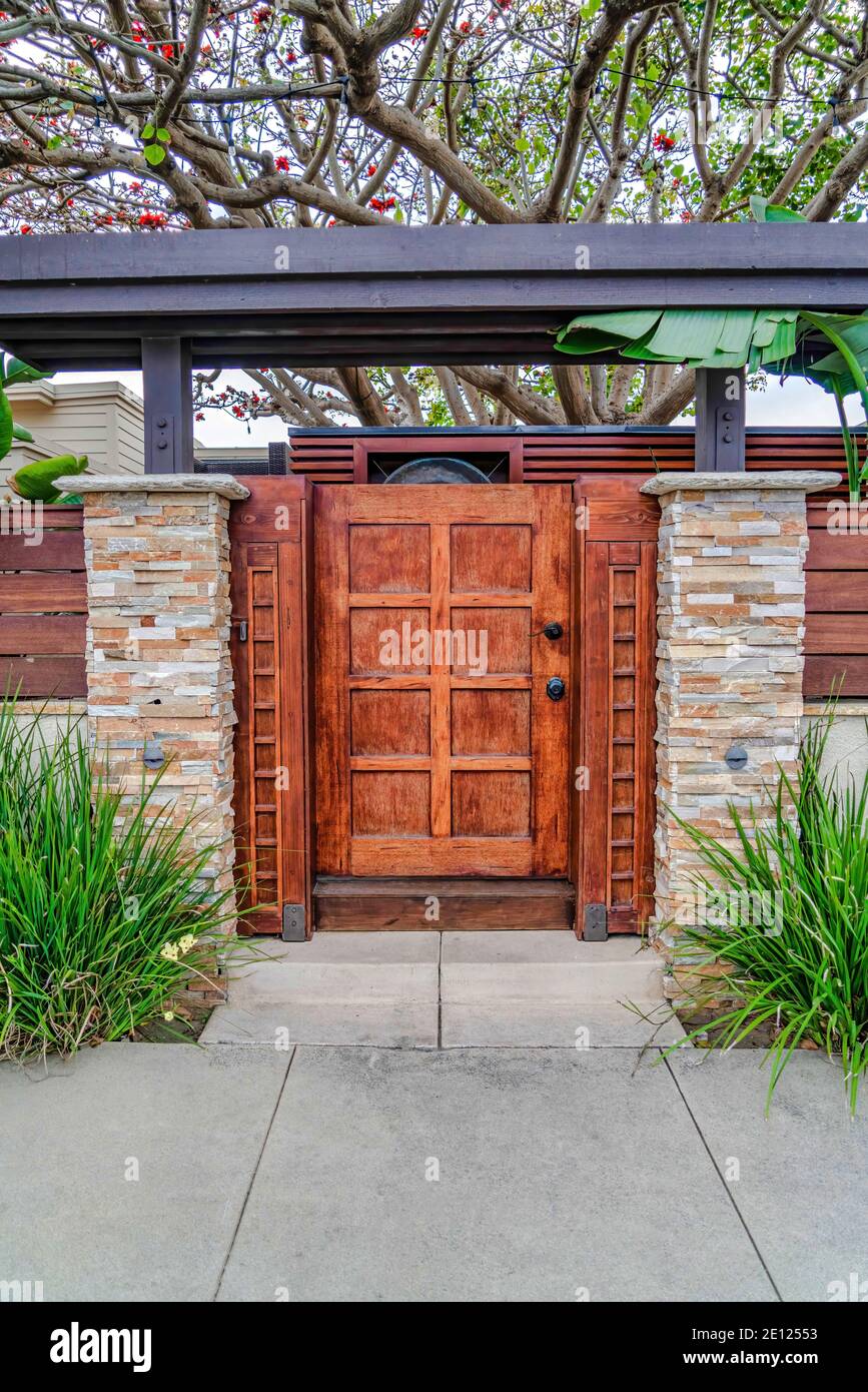 Brown wood gate with roof against brick posts and fence in San Diego ...