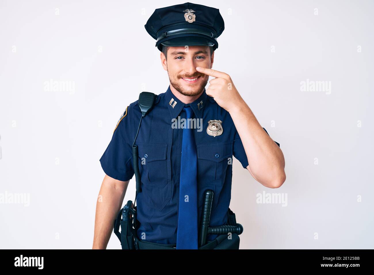 Young caucasian man wearing police uniform pointing with hand finger to ...