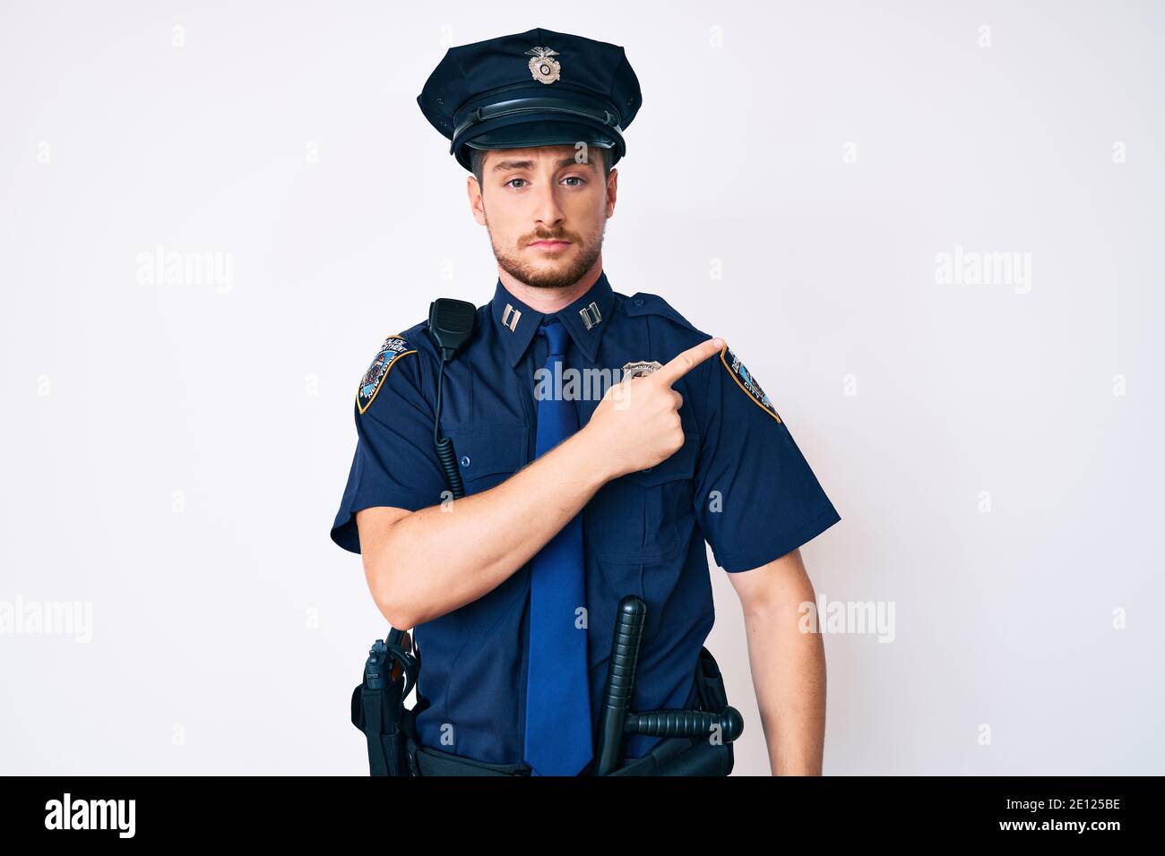 Young caucasian man wearing police uniform pointing with hand finger to ...
