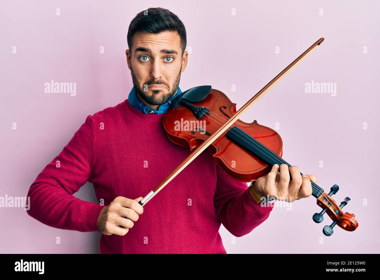 Young hispanic musician man playing violin depressed and worry for distress, crying angry and ...