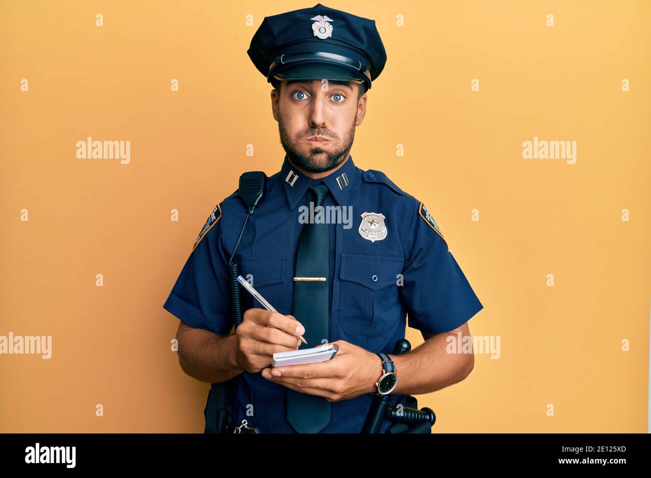 Handsome hispanic man wearing police uniform writing traffic fine ...
