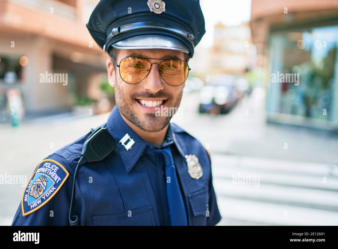 Young handsome hispanic policeman wearing police uniform smiling happy ...