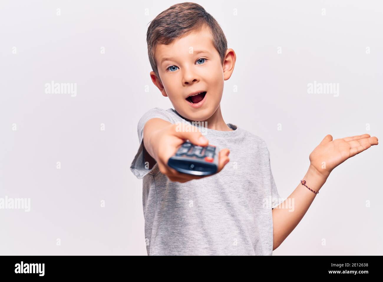 Cute blond kid holding television remote control celebrating ...