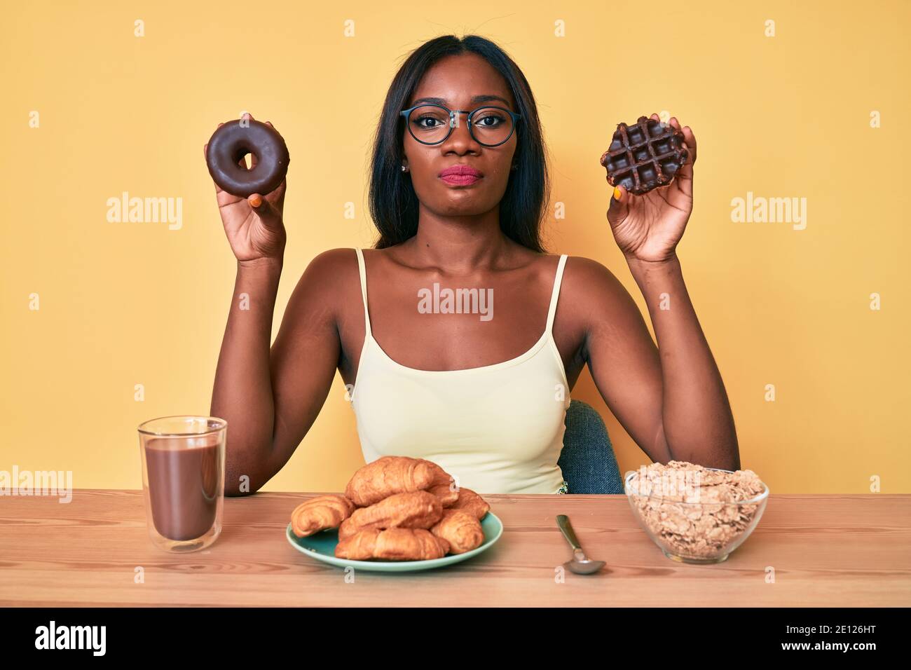 Young african american woman holding chocolate donut and waffle for ...