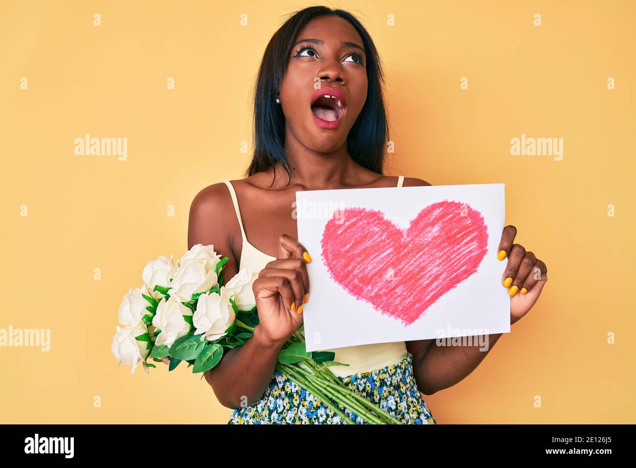 Young african american woman holding heart draw and flowers angry and ...