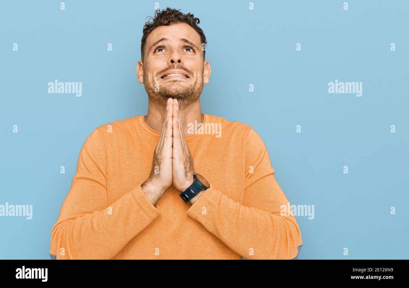 Young hispanic man wearing casual clothes begging and praying with ...
