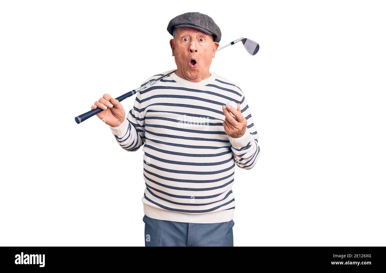 Senior handsome grey-haired man holding golf club and ball scared and ...