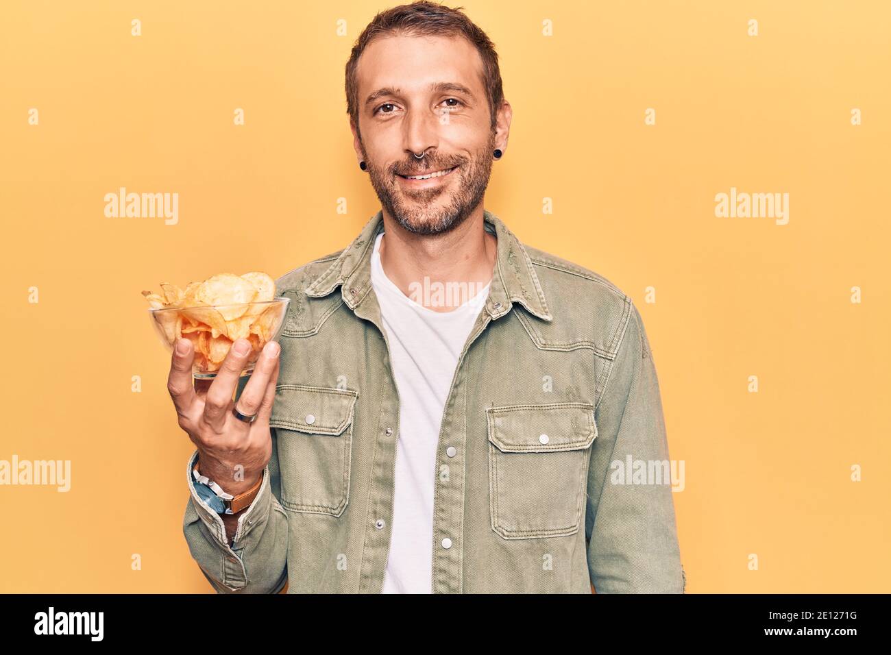 Young handsome man holding potato chip looking positive and happy ...