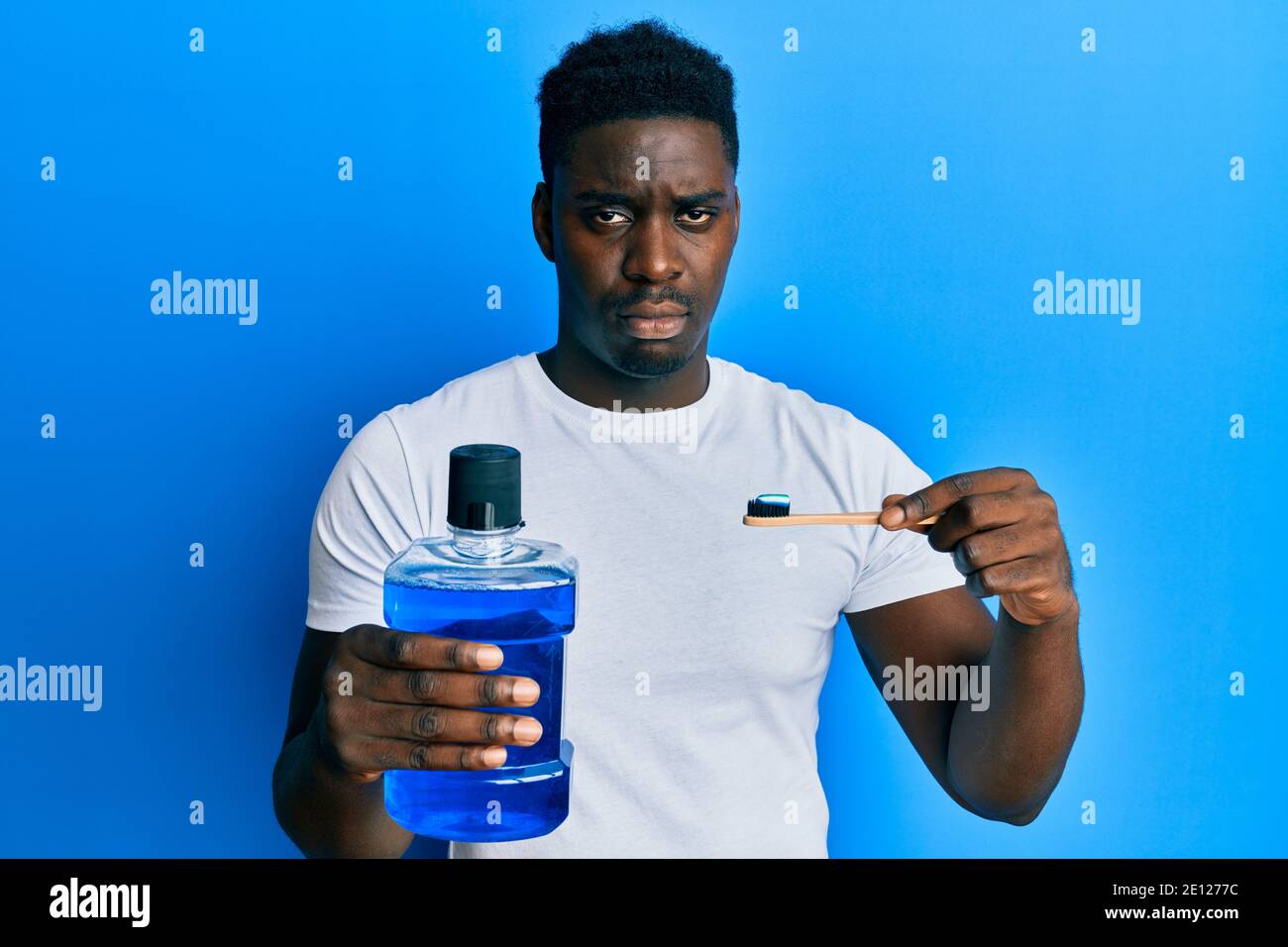 Handsome black man holding mouthwash and toothbrush for fresh breath ...