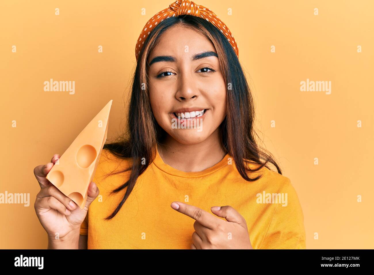Young latin woman eating emmental cheese smiling happy pointing with ...