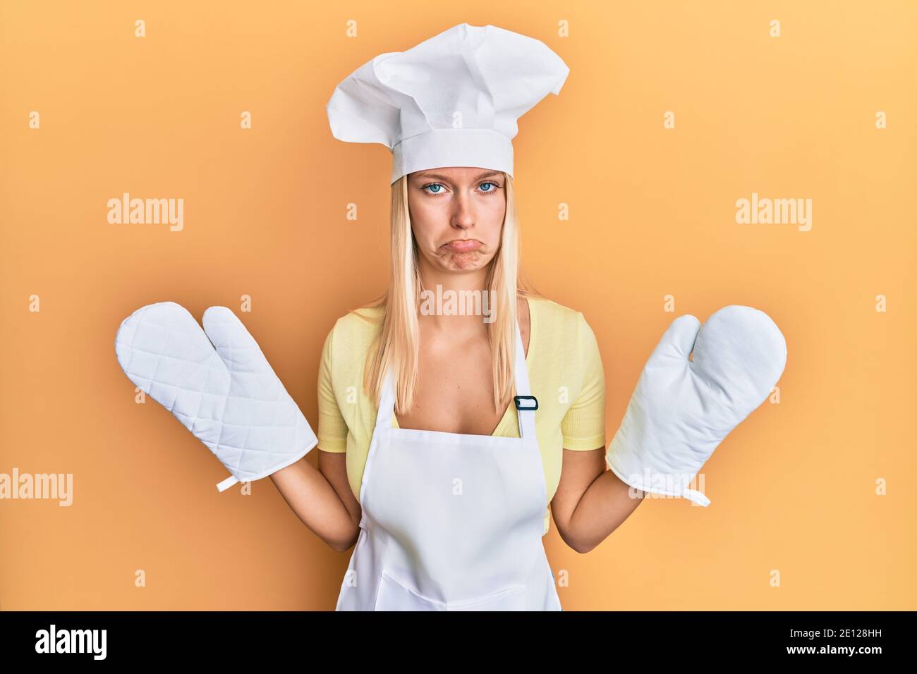 Young blonde girl wearing baker uniform and cook hat depressed and ...