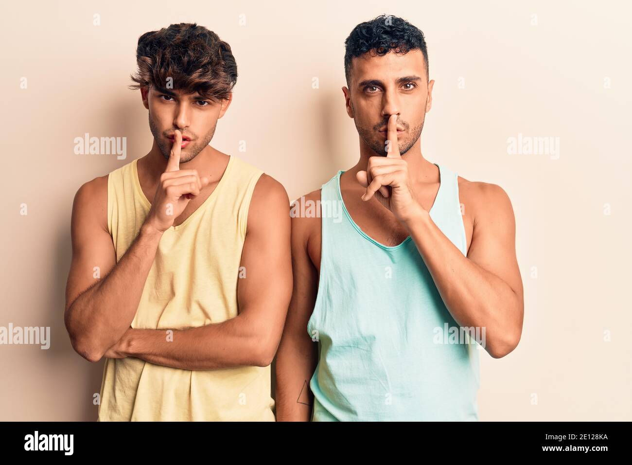 Young gay couple wearing casual clothes asking to be quiet with finger ...