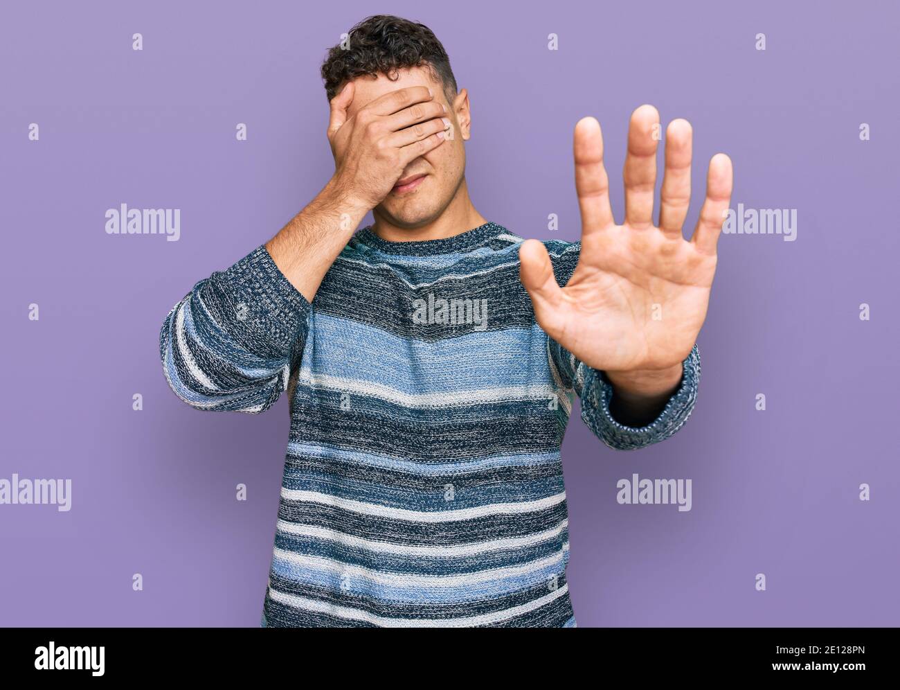 Hispanic young man wearing casual clothes covering eyes with hands and ...