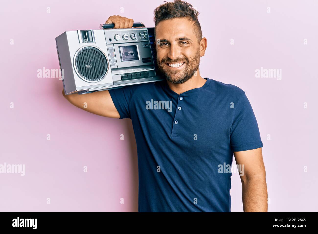Handsome man with beard holding boombox, listening to music looking ...