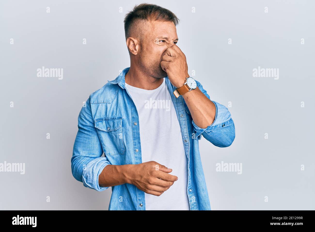 Handsome muscle man wearing casual denim jacket smelling something ...