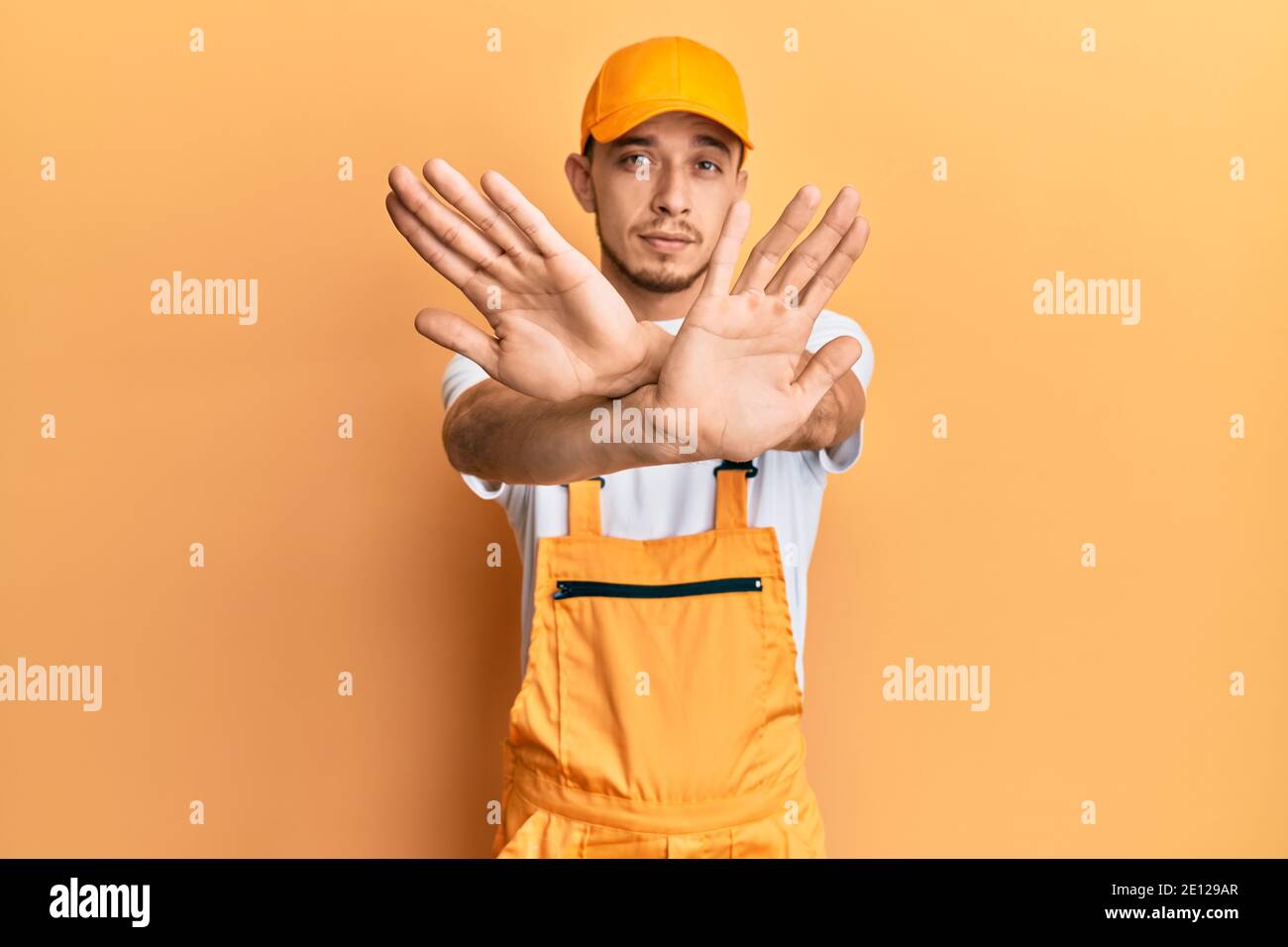 Hispanic young man wearing handyman uniform rejection expression ...