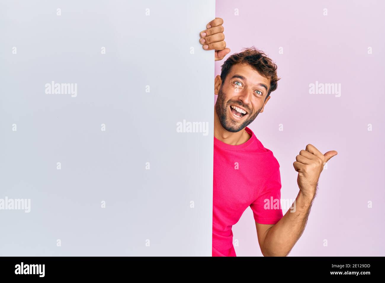 Handsome Man With Beard Holding Blank Empty Banner Pointing Thumb Up To