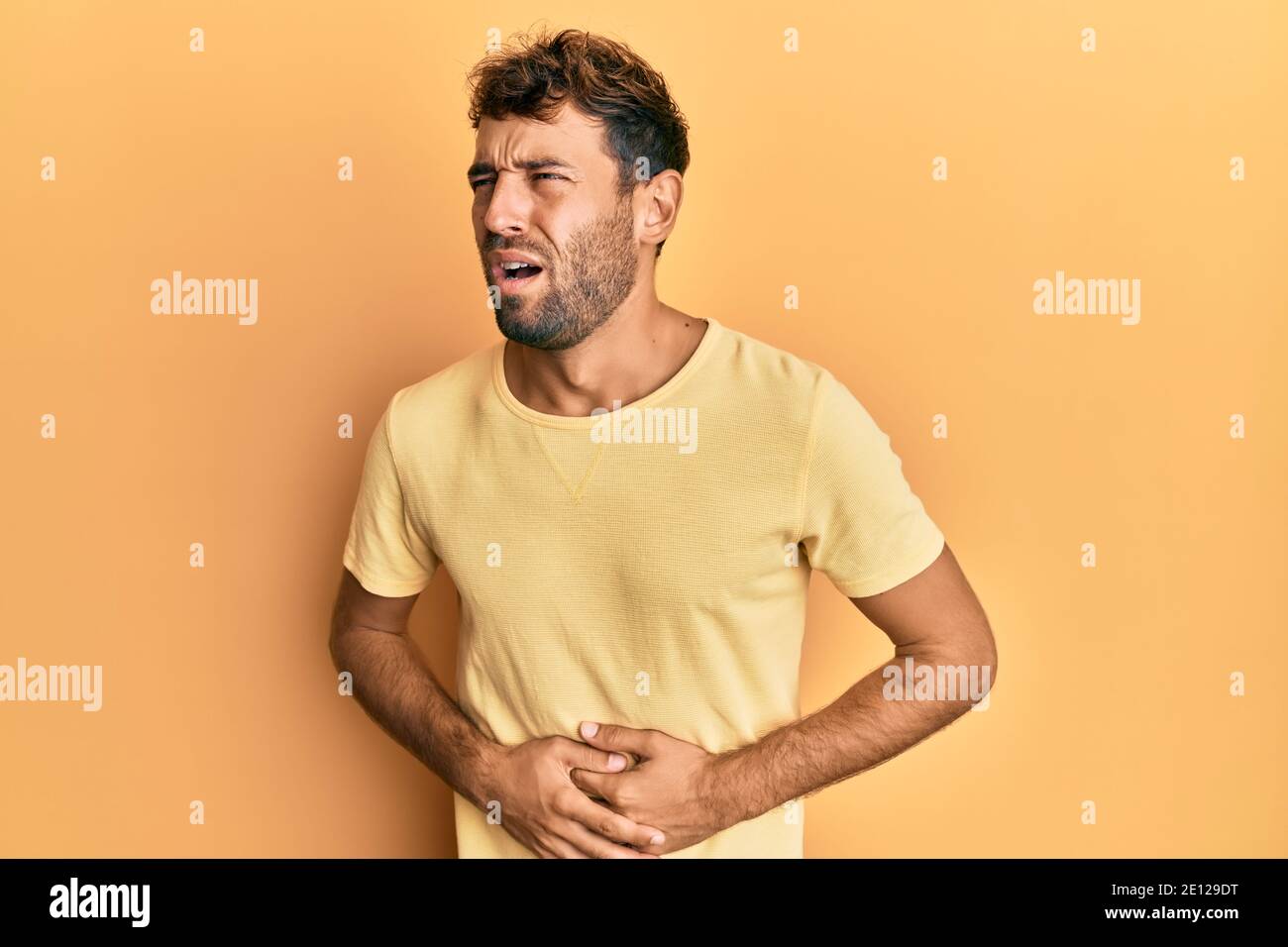Handsome man with beard wearing casual yellow tshirt over yellow ...